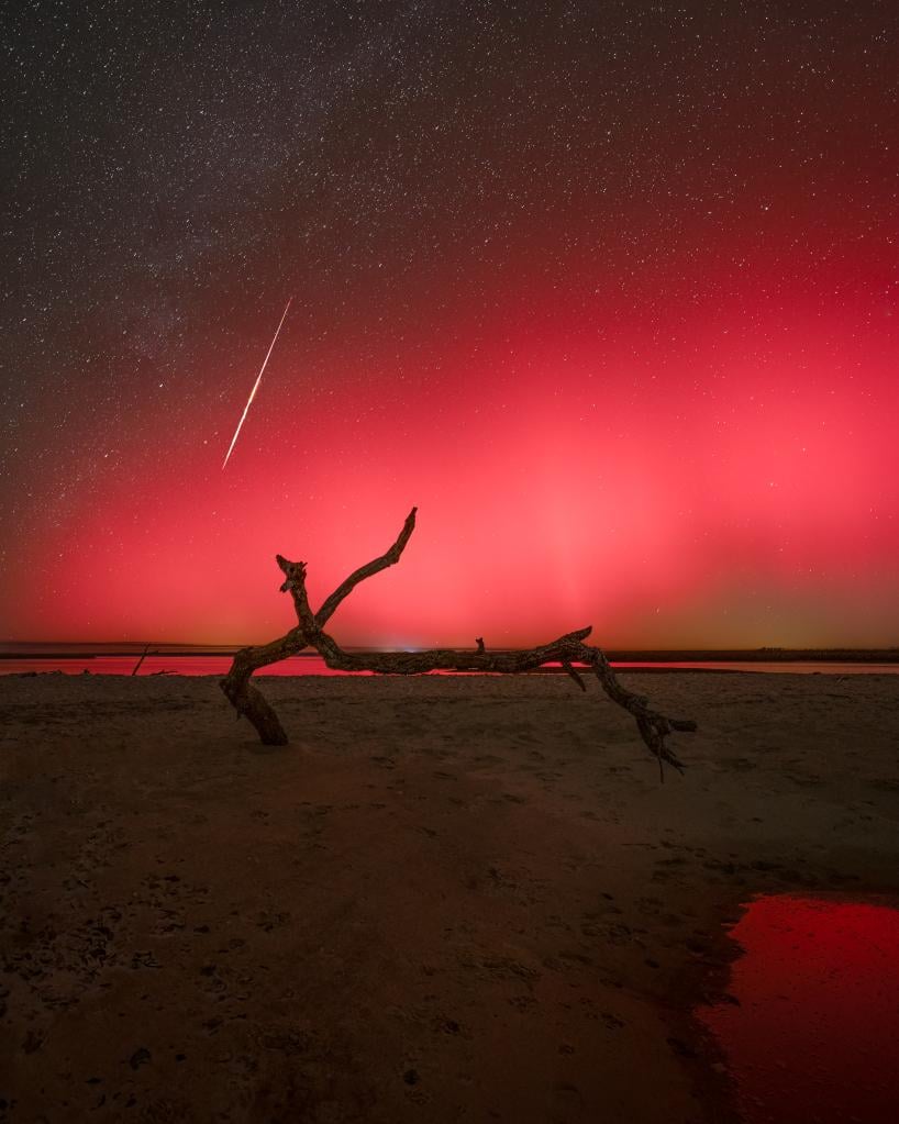 A meteor flashes through the aurora above the beach on Shired Island ...